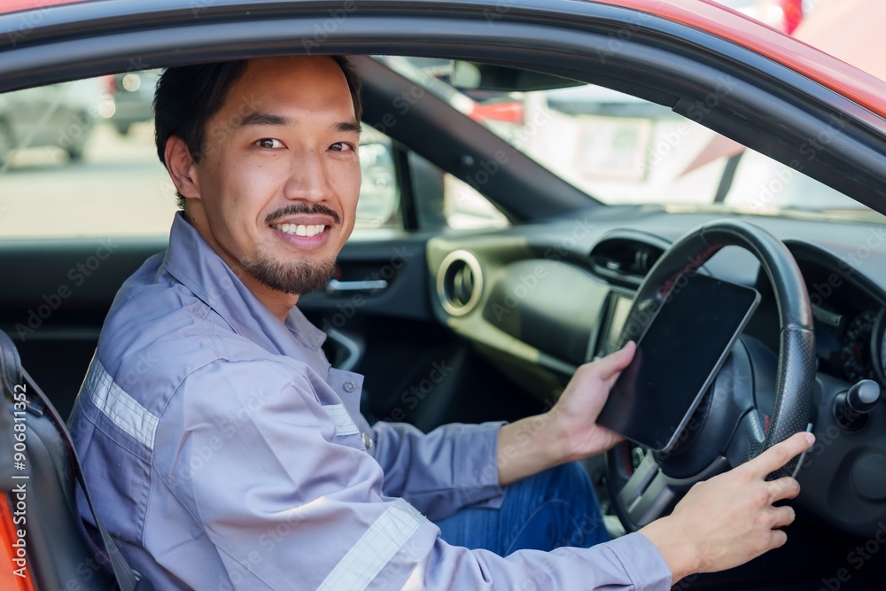 Asian male insurance officer in gray uniform sitting inside car holding ...