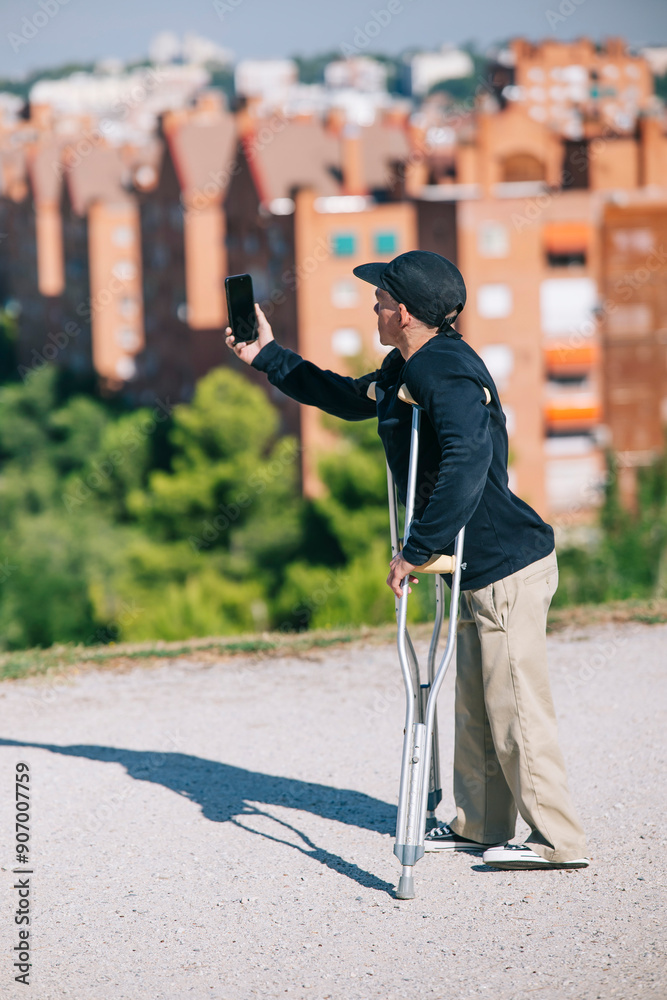 Person with a Motor Disability Using Crutches Looks at His Mobile Phone ...