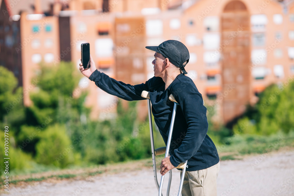 Person with a Motor Disability Using Crutches Looks at His Mobile Phone ...