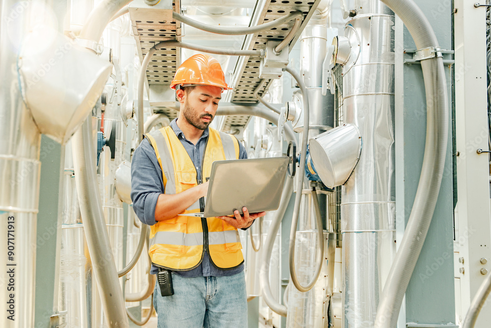 Male HAVC refrigeration system technician stands holding laptop ...