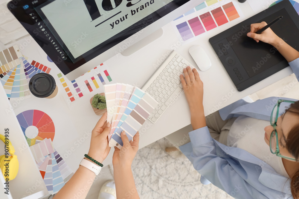 Female graphic designers working with color palettes at table in office ...