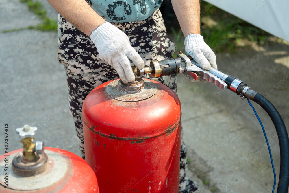A person connects the gas supply hose. Gas cylinder filling process. A ...