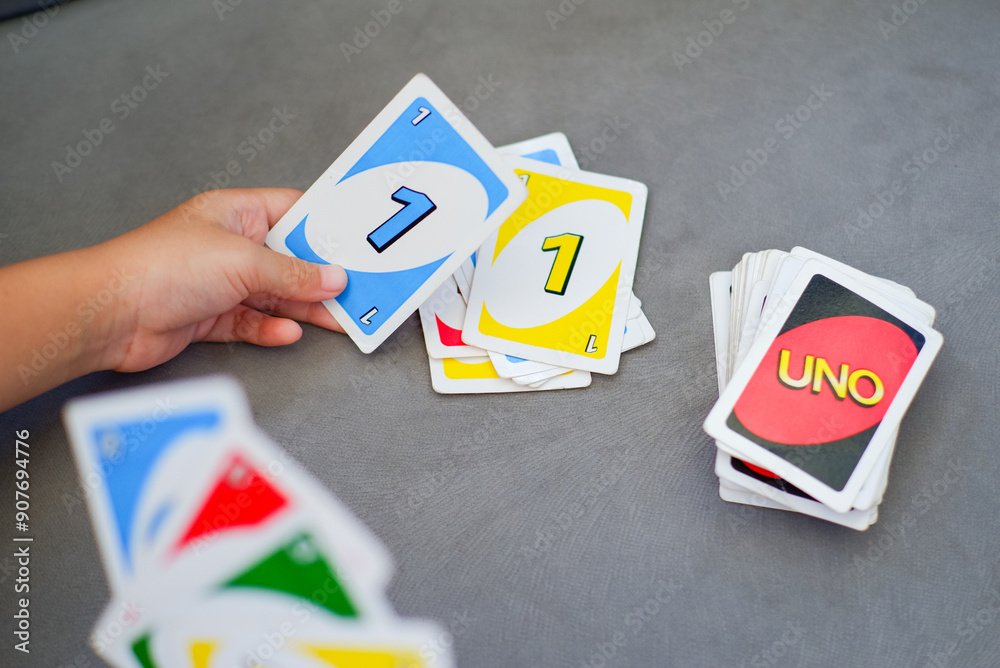 child hand taking one of set colorful Uno playing cards for a group ...