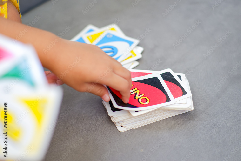 child hand taking one of set colorful Uno playing cards for a group ...