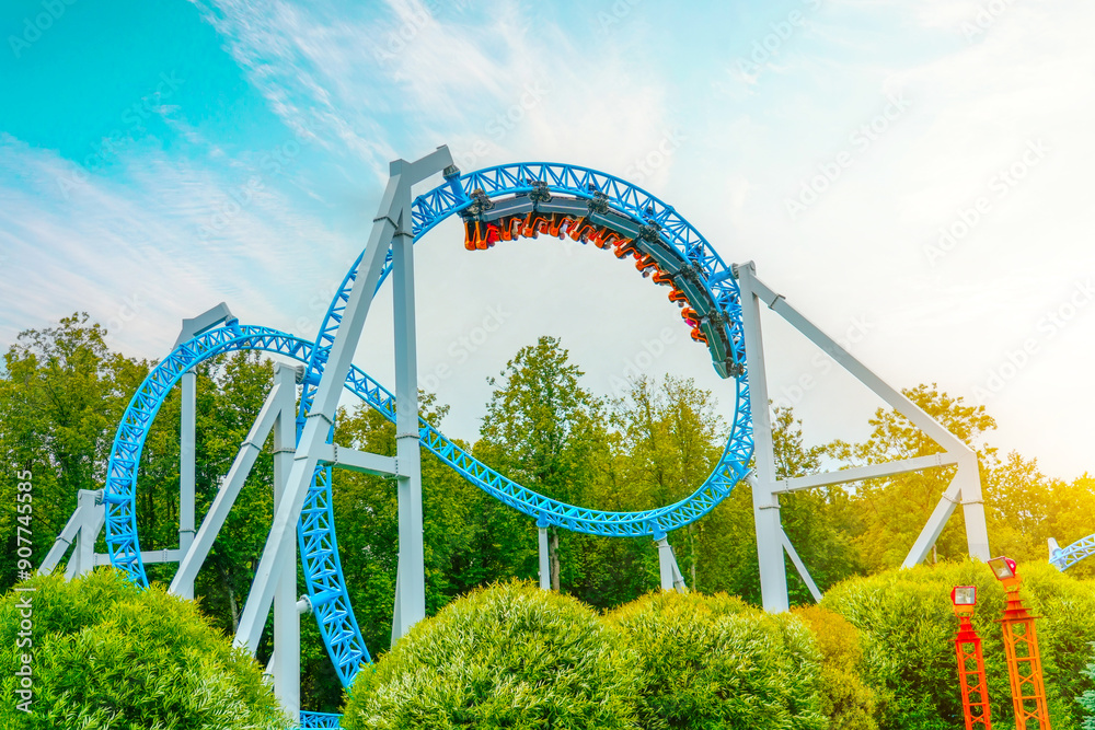 Roller coaster cart with people riding it goes through a loop upside ...