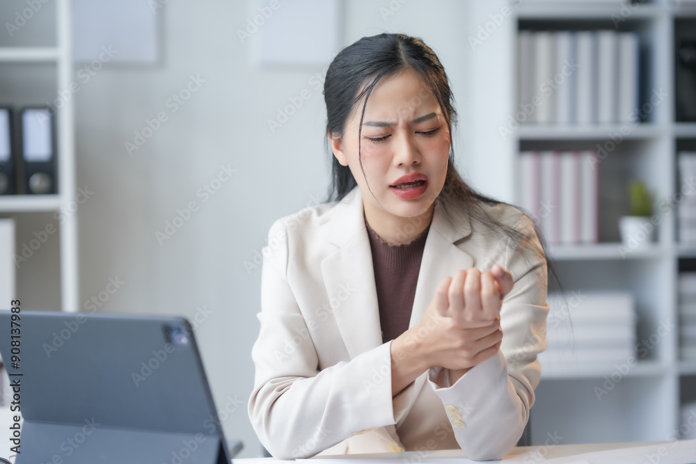 Stressed asian businesswoman with wrist pain at office desk ...