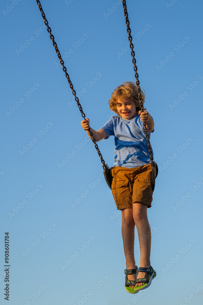 Little boy swinging on chain swing on city kids playground. Swing ride. Cute child having fun on ...