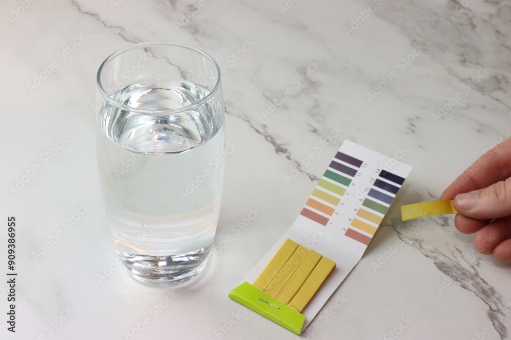 Woman doing the pH test with strips in a liquid glass and showing to ...