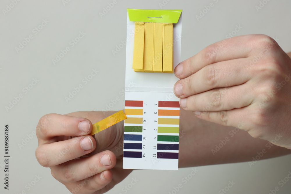 Woman holding the pH test and showing a strip with the color orange ...