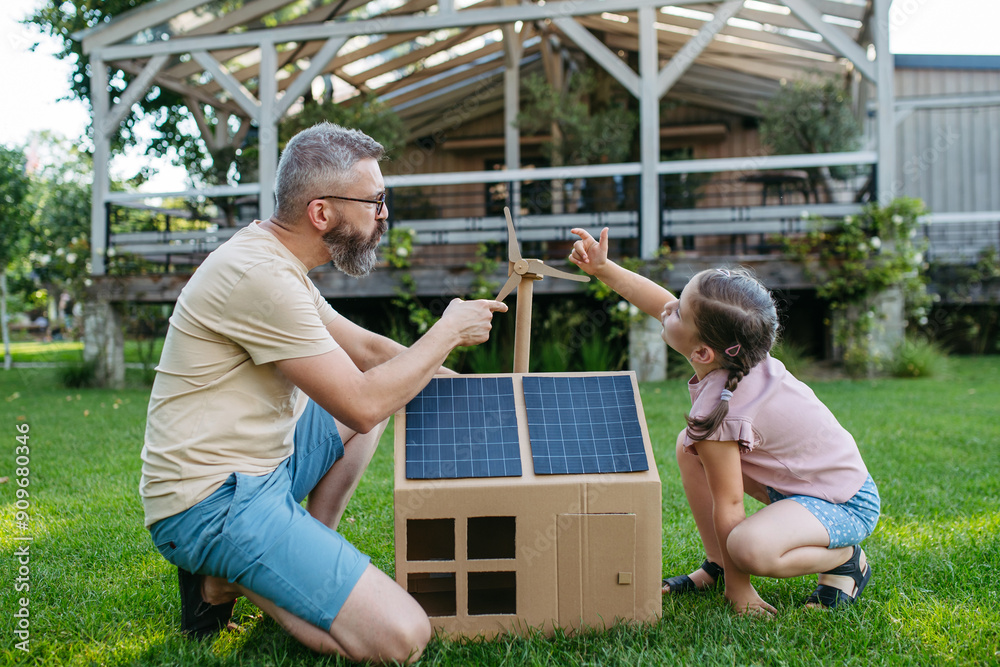 Dad and girl plying with house with solar panels on roof, learning ...