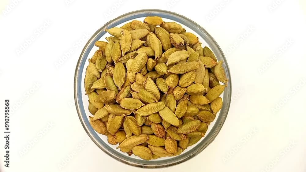 Green cardamom pods in a glass bowl isolated rotating on white ...