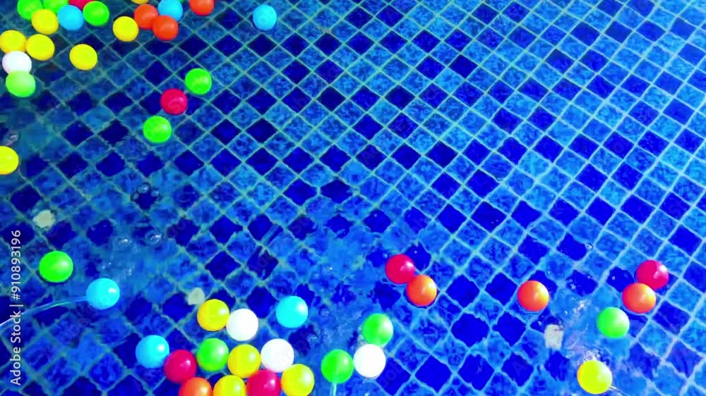 Various colored plastic balls in a swimming pool with blue water ...