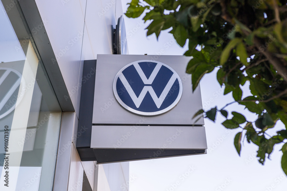 Volkswagen logo atop a service center, captured against clear sky. VW ...