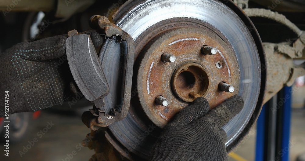 Auto mechanic shows uneven wear of the brake disc in a passenger car ...