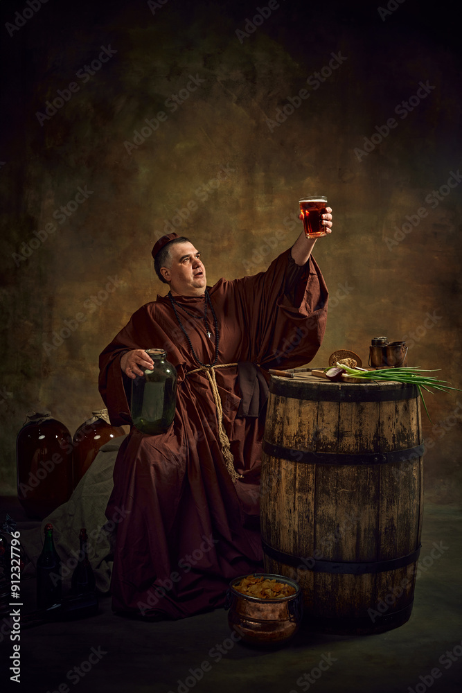 Man, medieval monk lifting glass of beer, pint of ale against dark ...