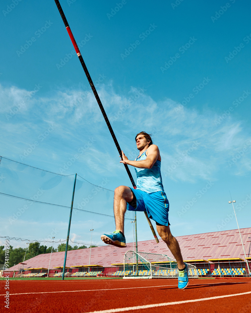 Pole vaulter in blue uniform, demonstrating strength and determination ...