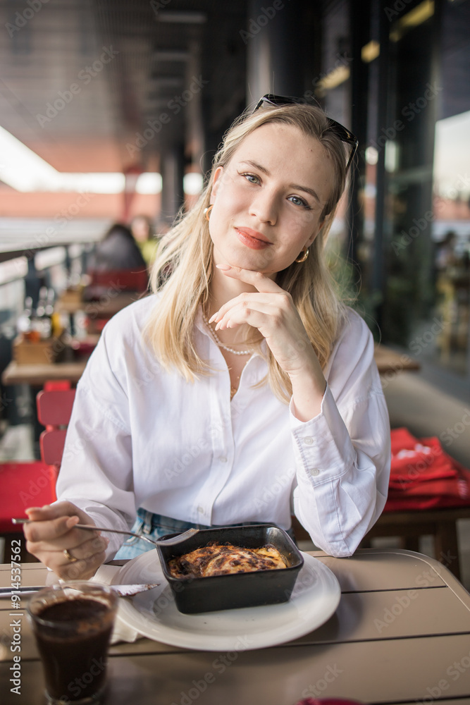 Blonde gen z woman eating lasagna in the cafe on break. Gen z girl ...