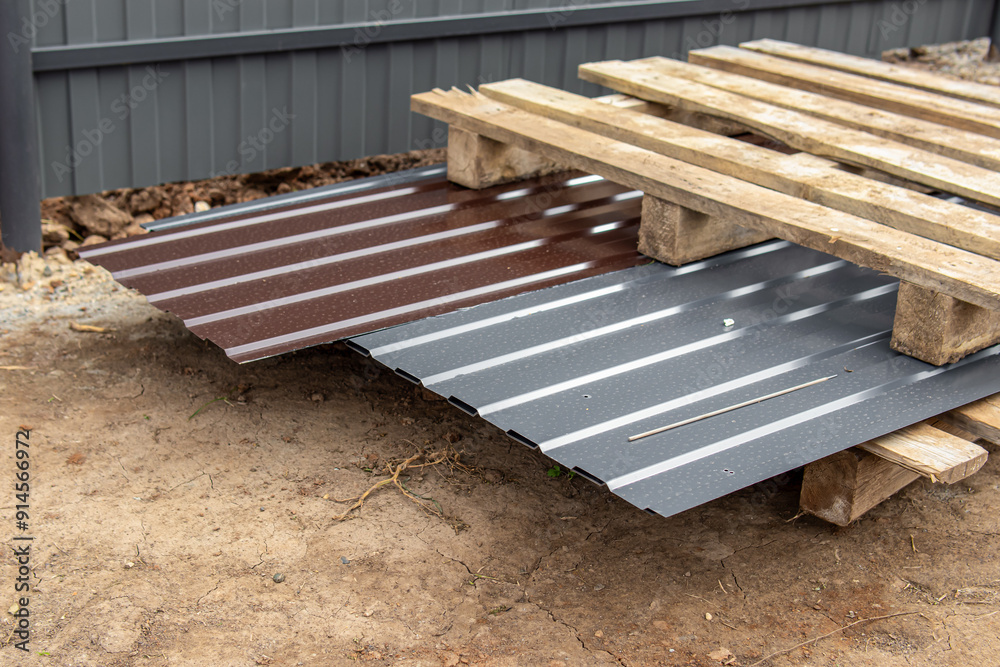 Installing profiled sheet fence. Grey and brown corrugated board at the ...