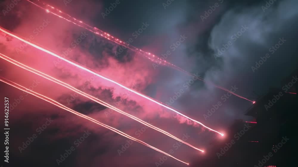 Bright red laser beams cut through a dark night sky filled with clouds ...