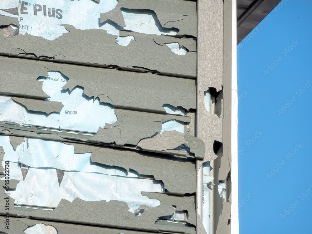 A close-up of a exterior wall with significant damage to its siding ...