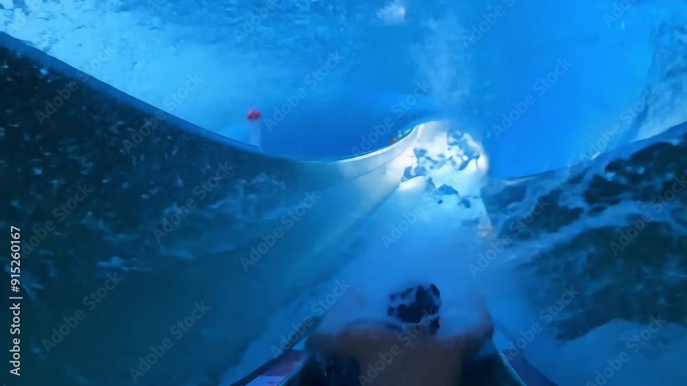 Happy boy riding down slide in water aqua park. Cheerful child have fun ...