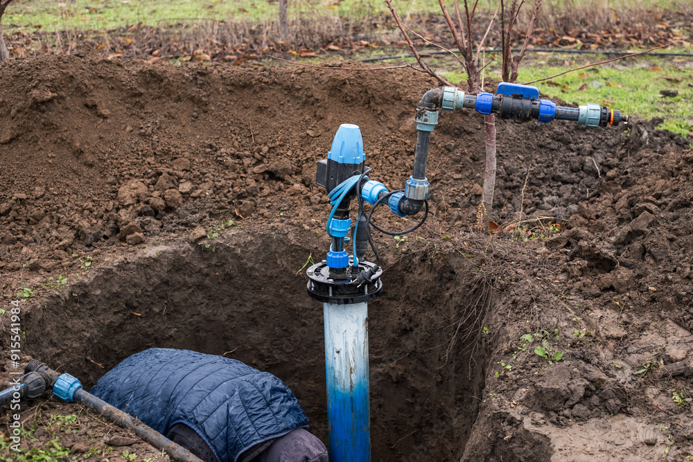 A worker installs a water intake unit in a well. Installation of the ...