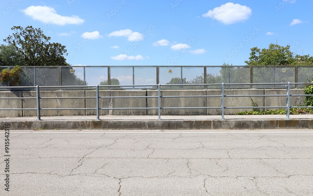 Safety railing protecting sidewalk. Concrete fence with wire mesh on ...