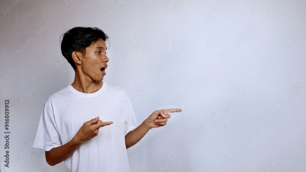 shocked asian male youth wearing white shirt gestures hand pointing to ...