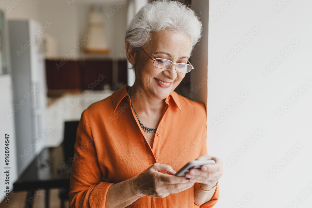 Portrait of cheerful grandma holding smartphone in hands, chatting with ...