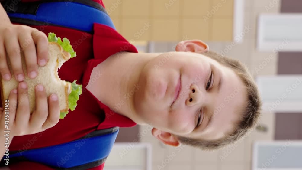 child kid boy eats sandwich with a school backpack on her back ...