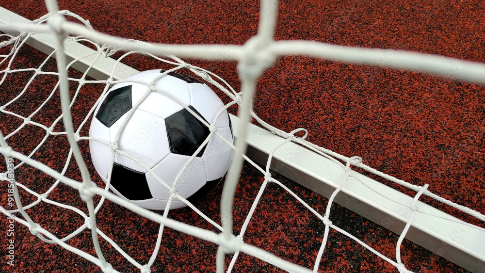 Soccer ball in the goal net on a futsal football field with rubber ...