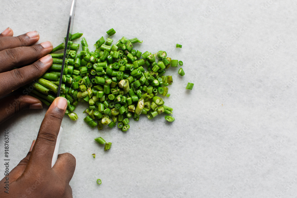 Overhead view of green beans being diced on a marble countertop, top ...