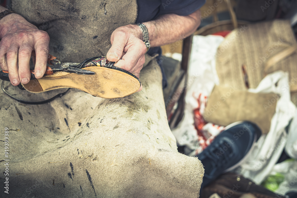 Close-up of the hands of an old master shoemaker in a leather apron ...