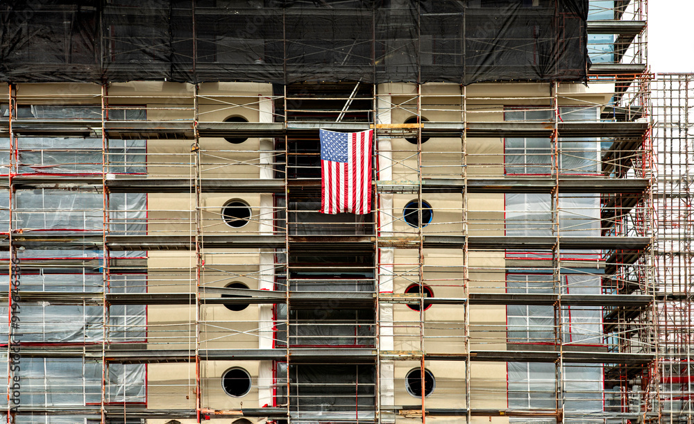 An American flag hanging from scaffolding on a large building under ...