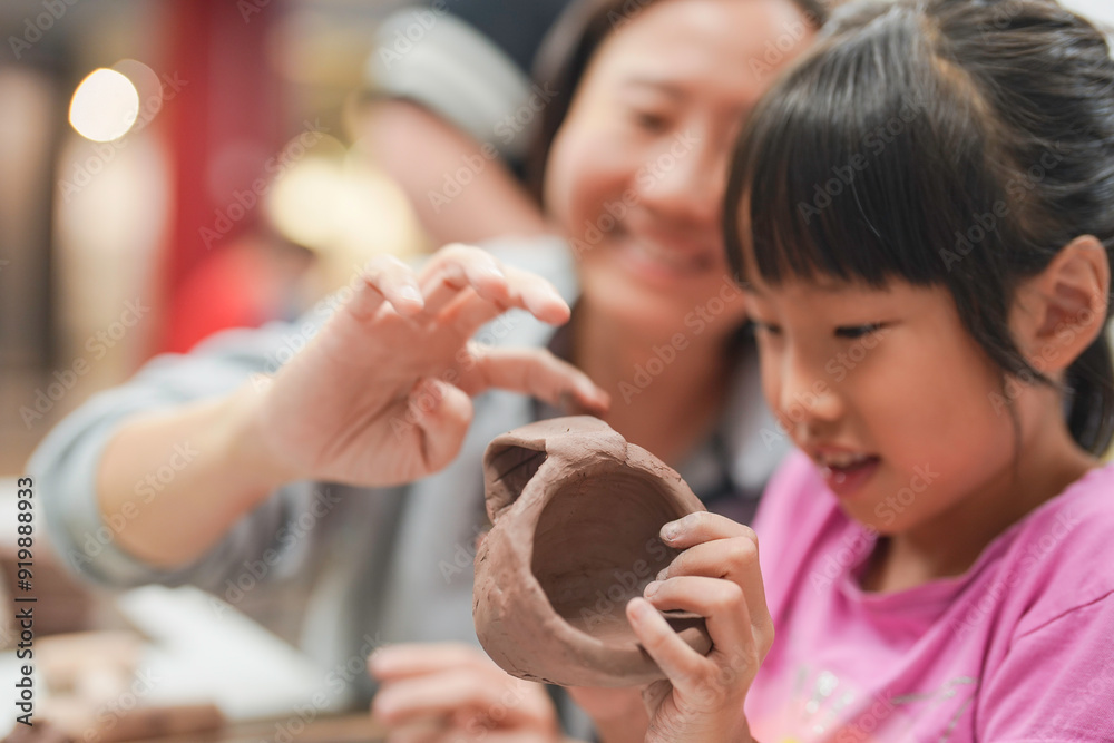 A young girl is joyfully engaged in a pottery activity, carefully ...