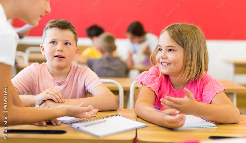 Interested preteen pupils divided into small groups, discussing ...