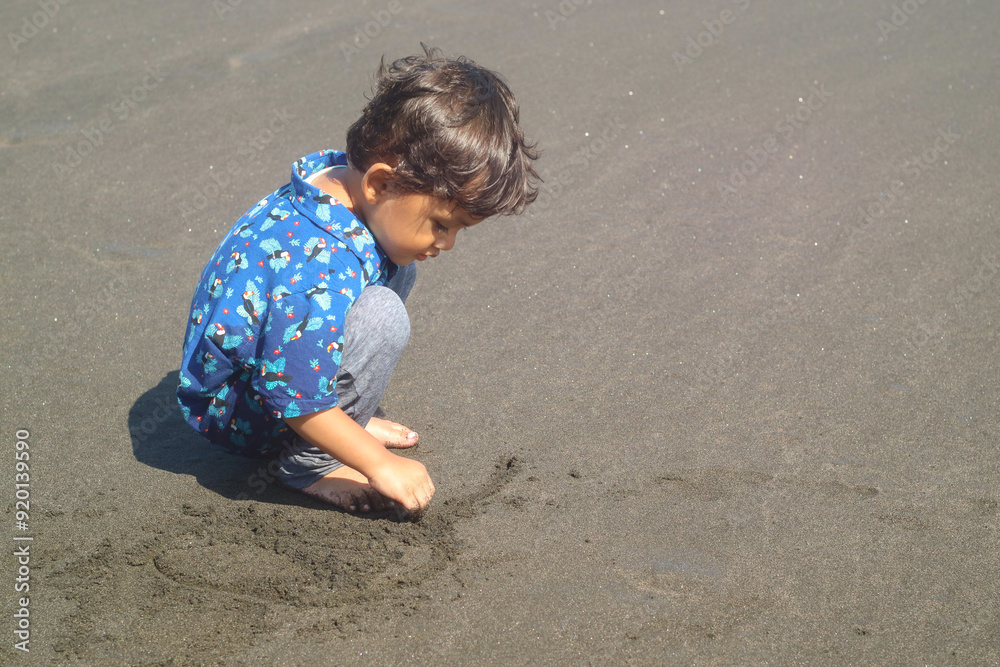 Cute child drawing picture on a sand playing outdoor on summer beach ...