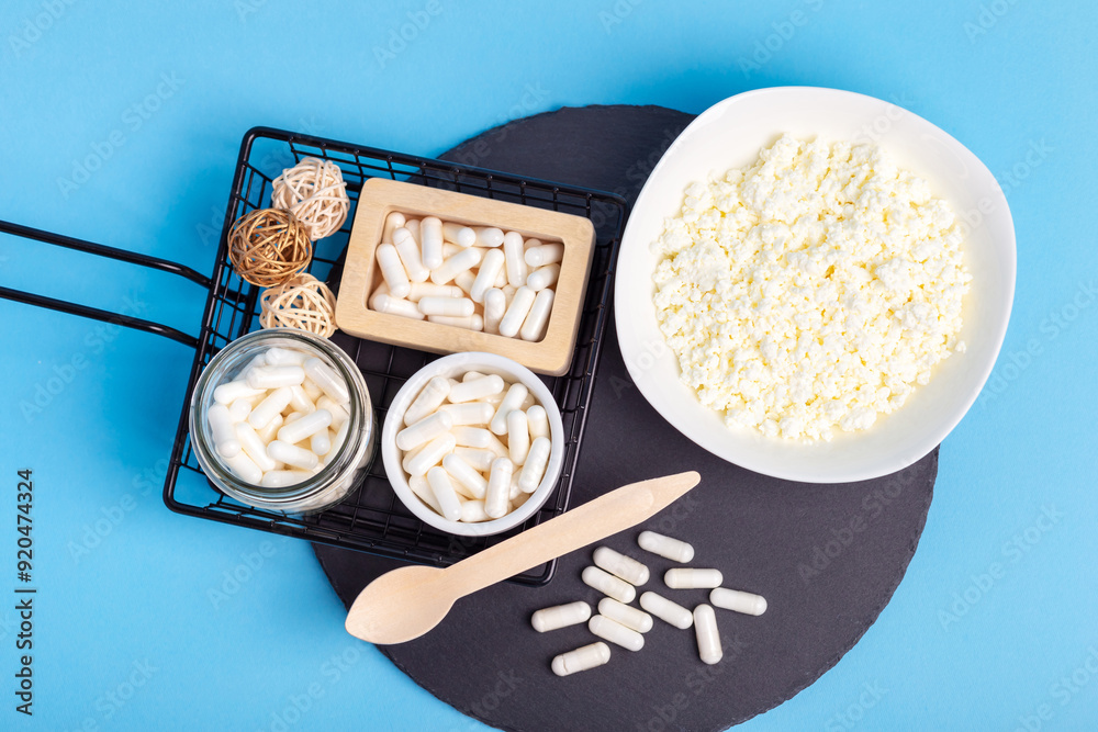 Many lactase tablets, cottage cheese and a wooden spoon on a black ...