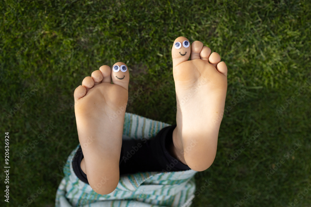 bare feet of child with funny faces painted on big toes. positive ...