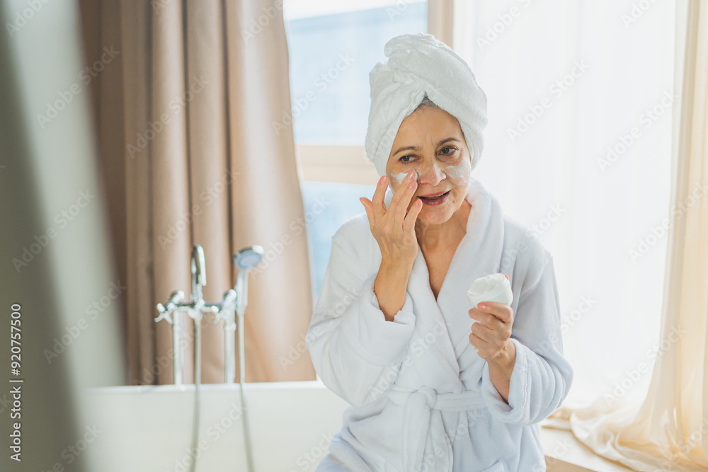 Mature adult old woman applying nourishing anti age face cream doing ...