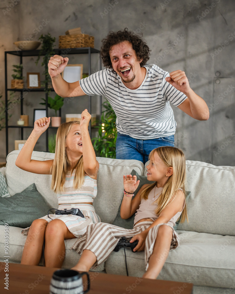 father cheer to his daughters while they play video games on joystick ...