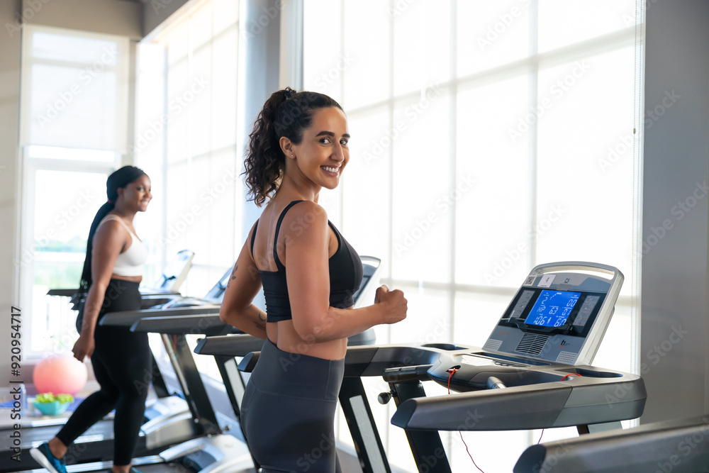 Jogging on treadmill in a gym. beautiful young hispanic woman wearing ...