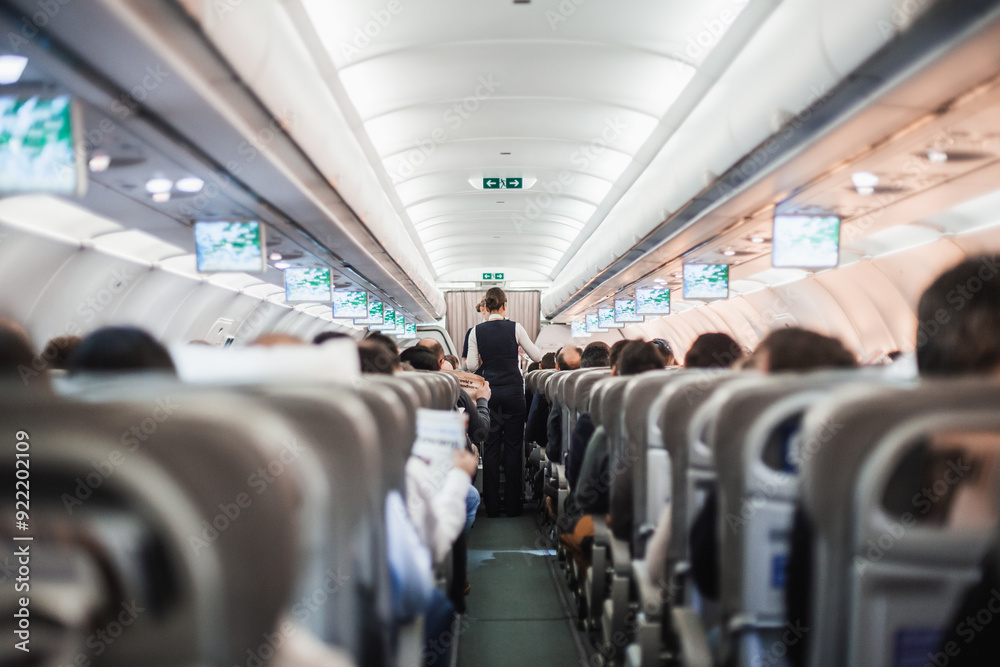 Interior of airplane with passengers on seats and stewardess in uniform ...