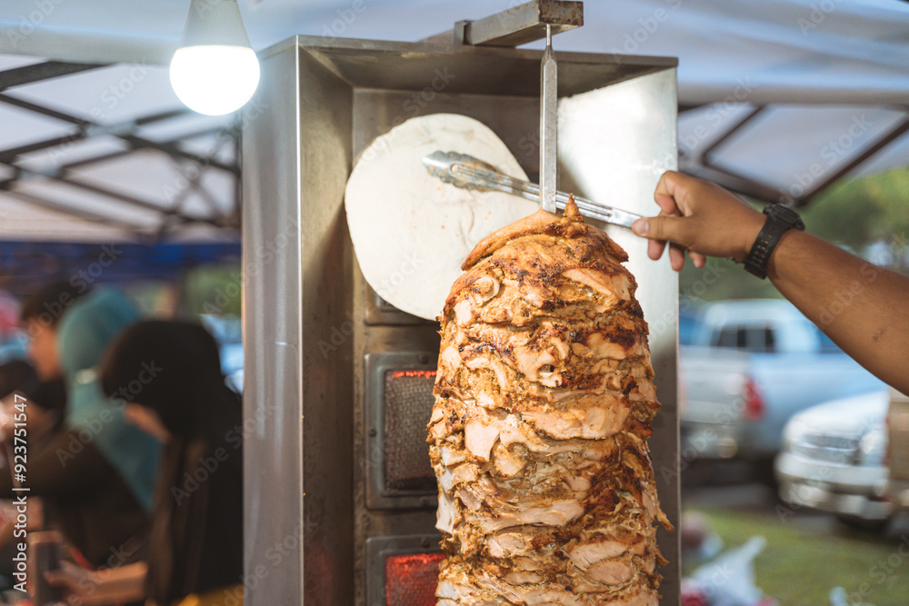 Hand preparing shawarma at a street food stall, cooking meat on a ...