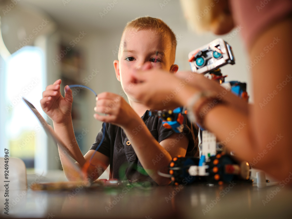 A young boy and a woman are engaged in building a robot together at a ...