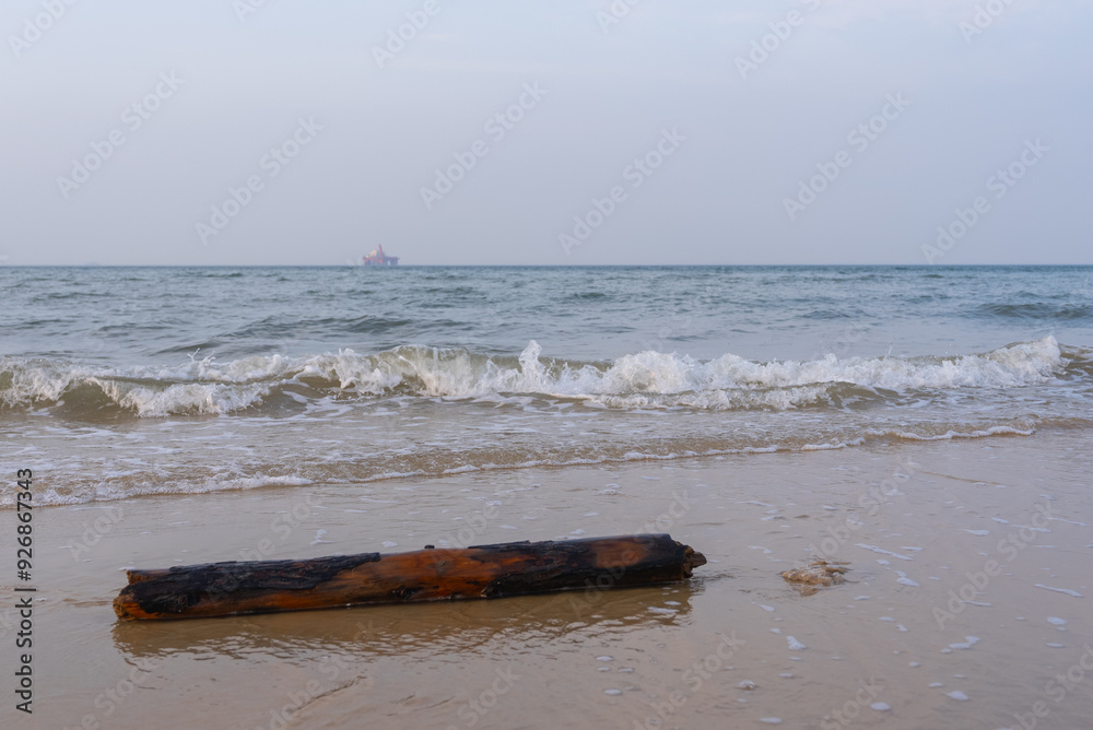 log lying on the beach, clear wave patterns, aquaculture facility in ...