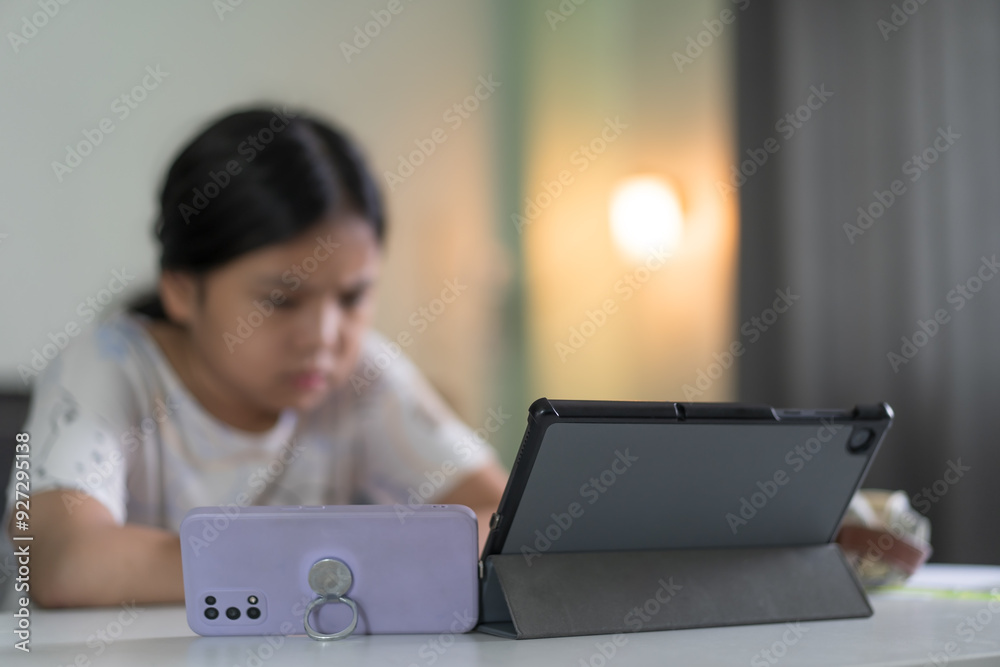 closeup tablet and smartphone with blur asian child frown stressed or ...