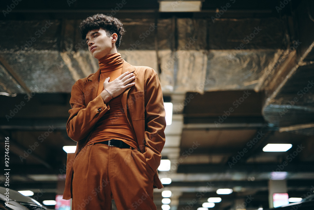 Stylish young man in rust colored suit poses confidently in a modern ...