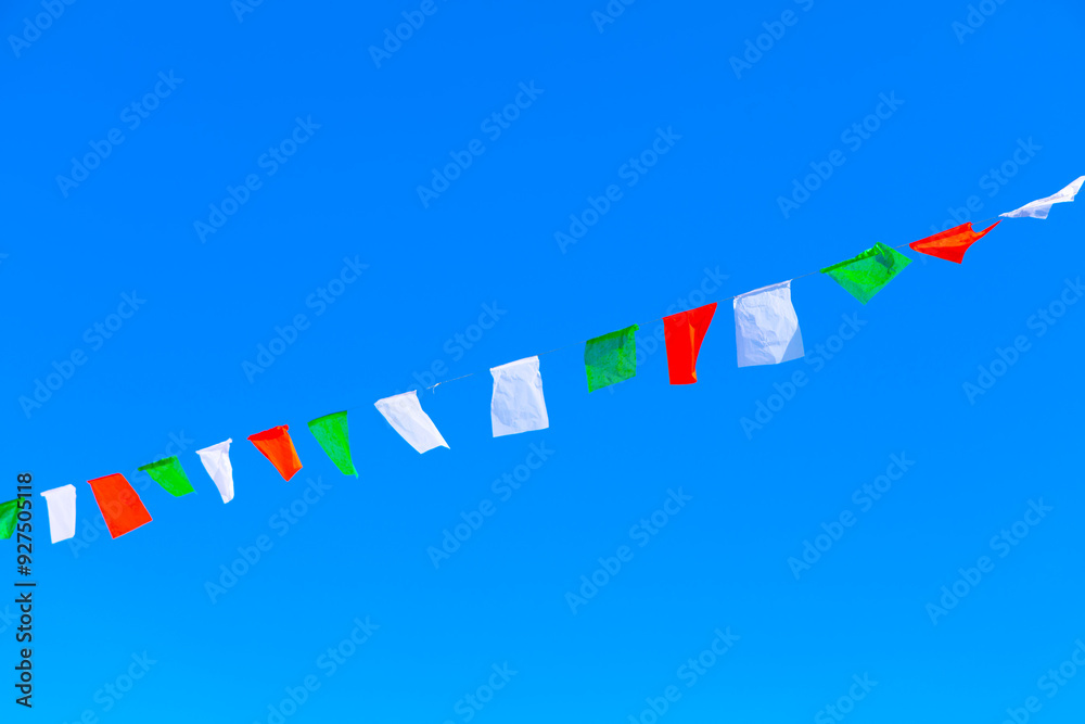 Colorful flags hanging high against a clear blue sky, showcasing a ...