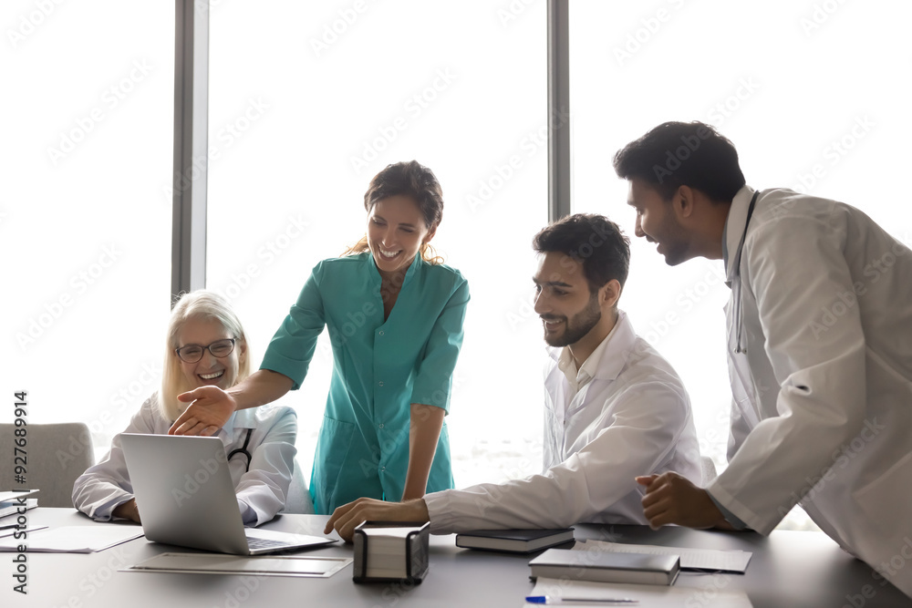 Multi-ethnic young and middle-aged laughing internists using laptop ...